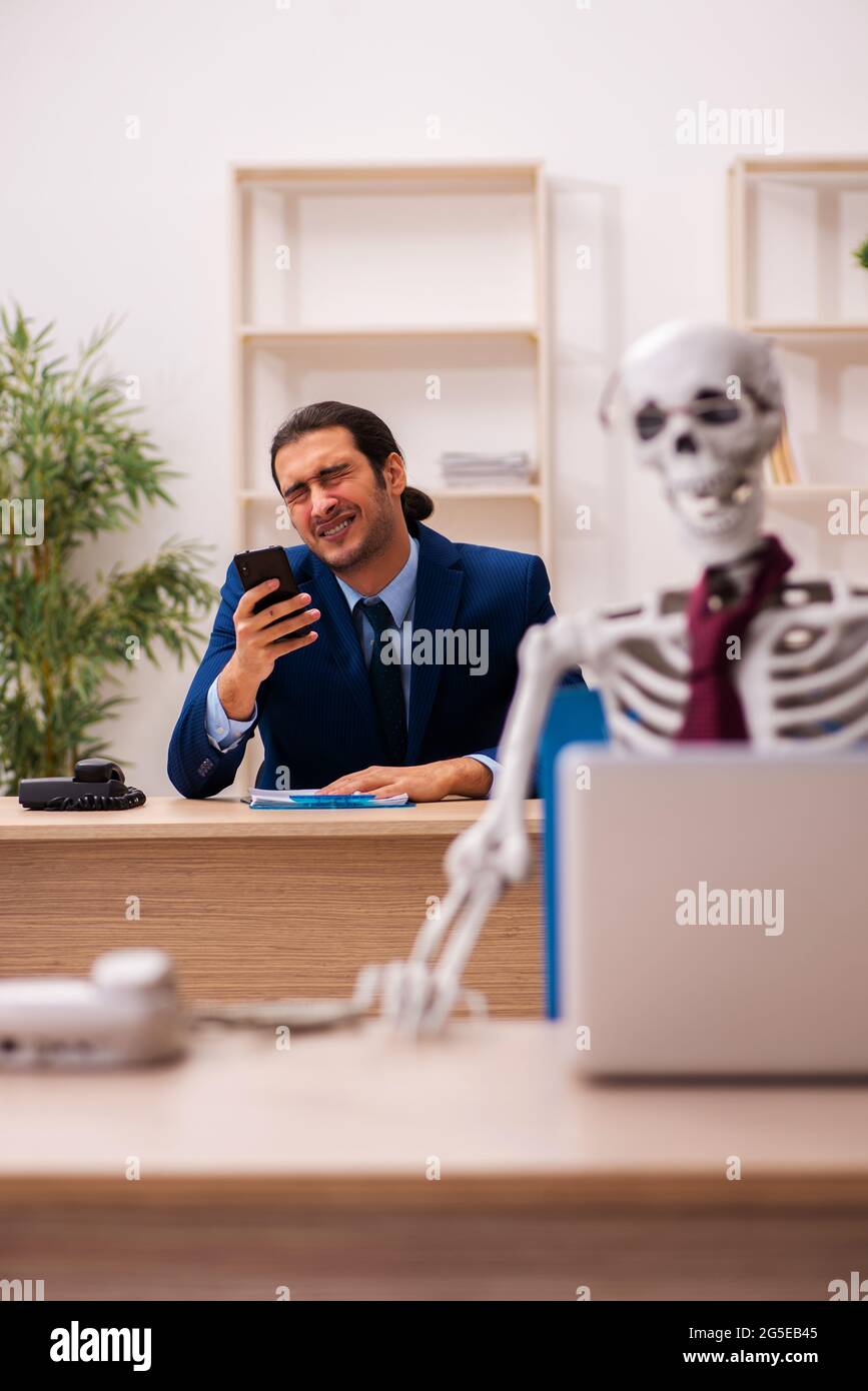 Dead employee working in the office in funny concept Stock Photo - Alamy