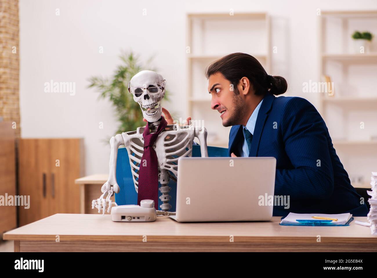 Dead employee working in the office in funny concept Stock Photo - Alamy