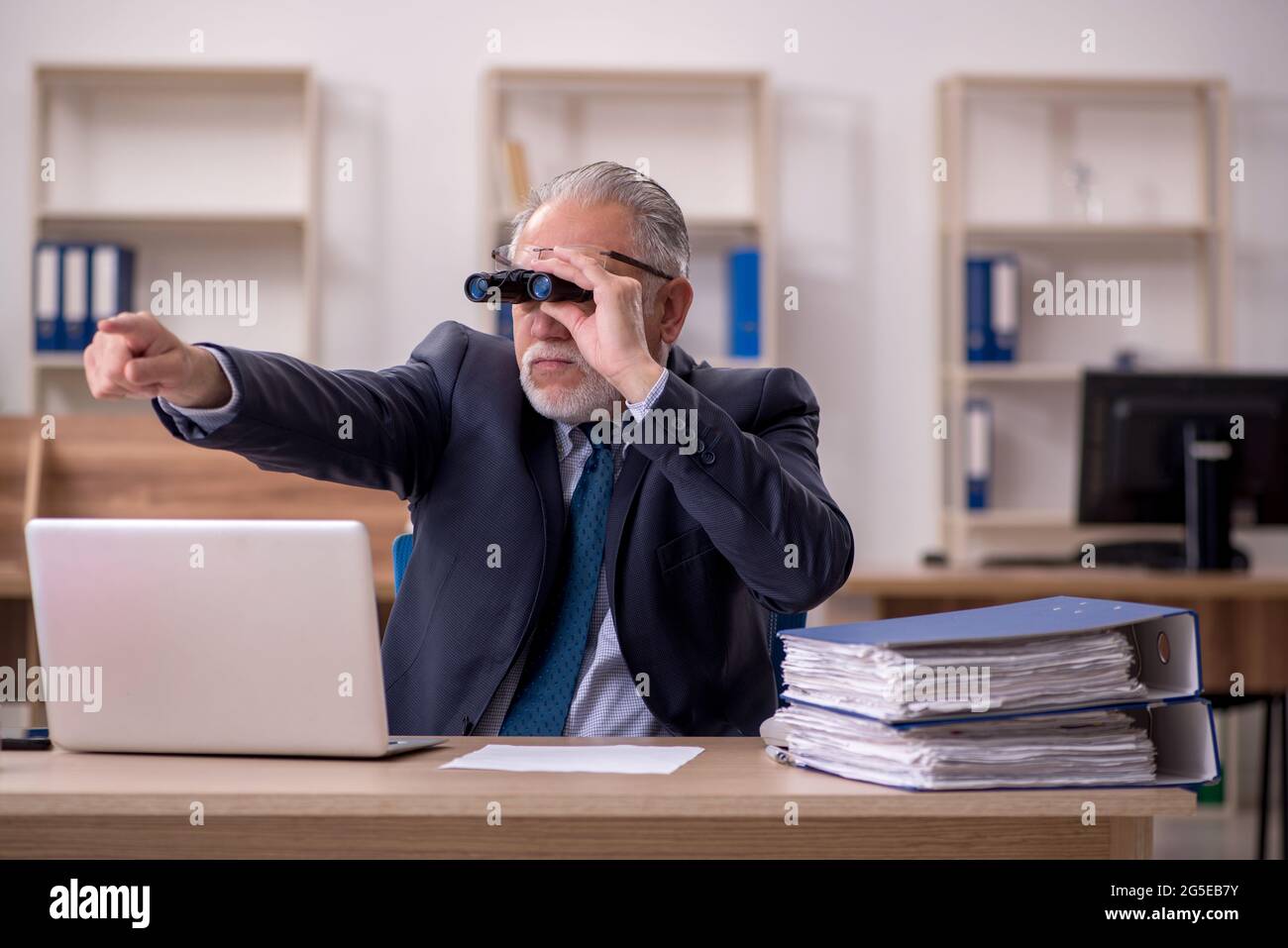 Old employee auditor holding binoculars at workplace Stock Photo - Alamy