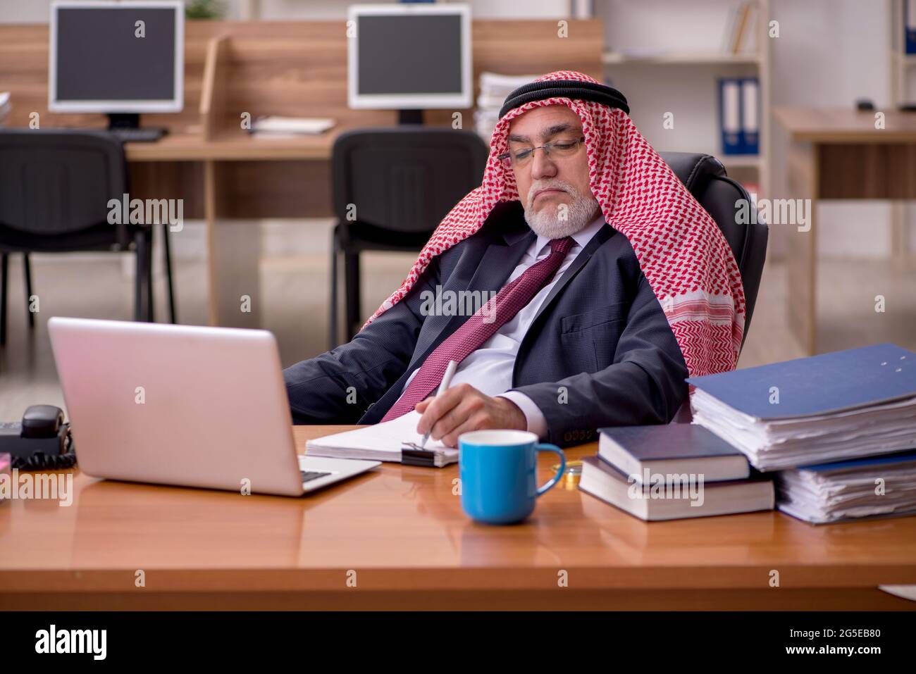 Old male arab employee sitting at workplace Stock Photo - Alamy