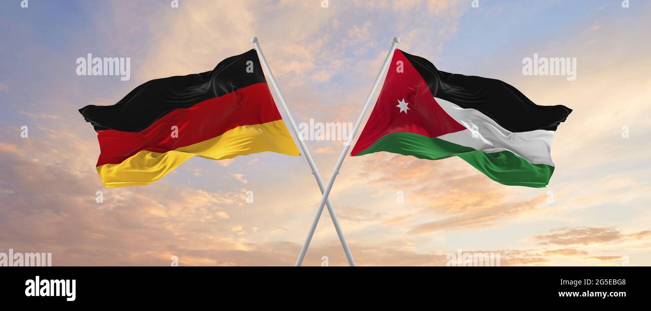 flags of Germany and Jordan waving in the wind on flagpoles against sky ...