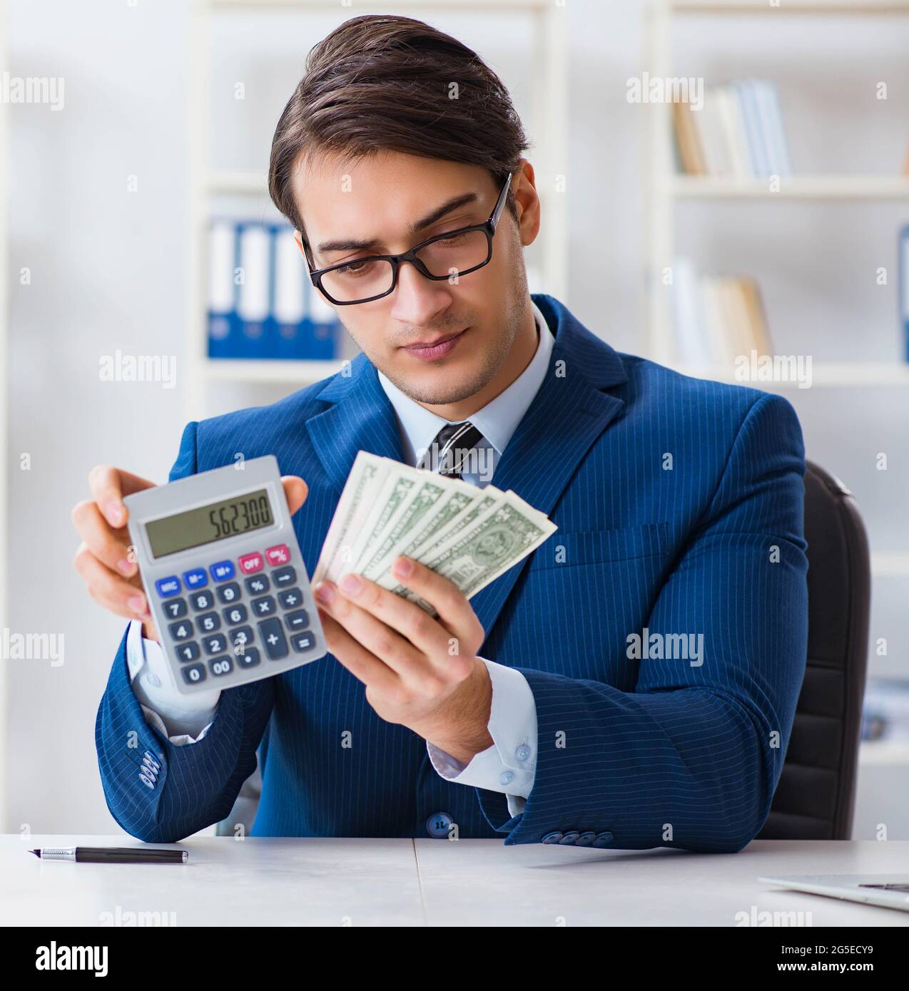 The accountant calculating dollars with calculator in office Stock ...