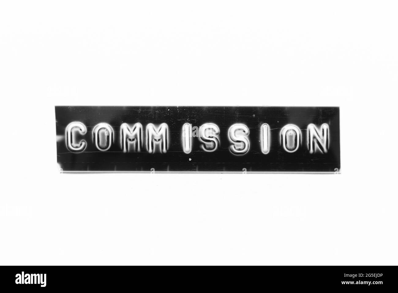 Embossed letter with word commission in black banner on white paper ...