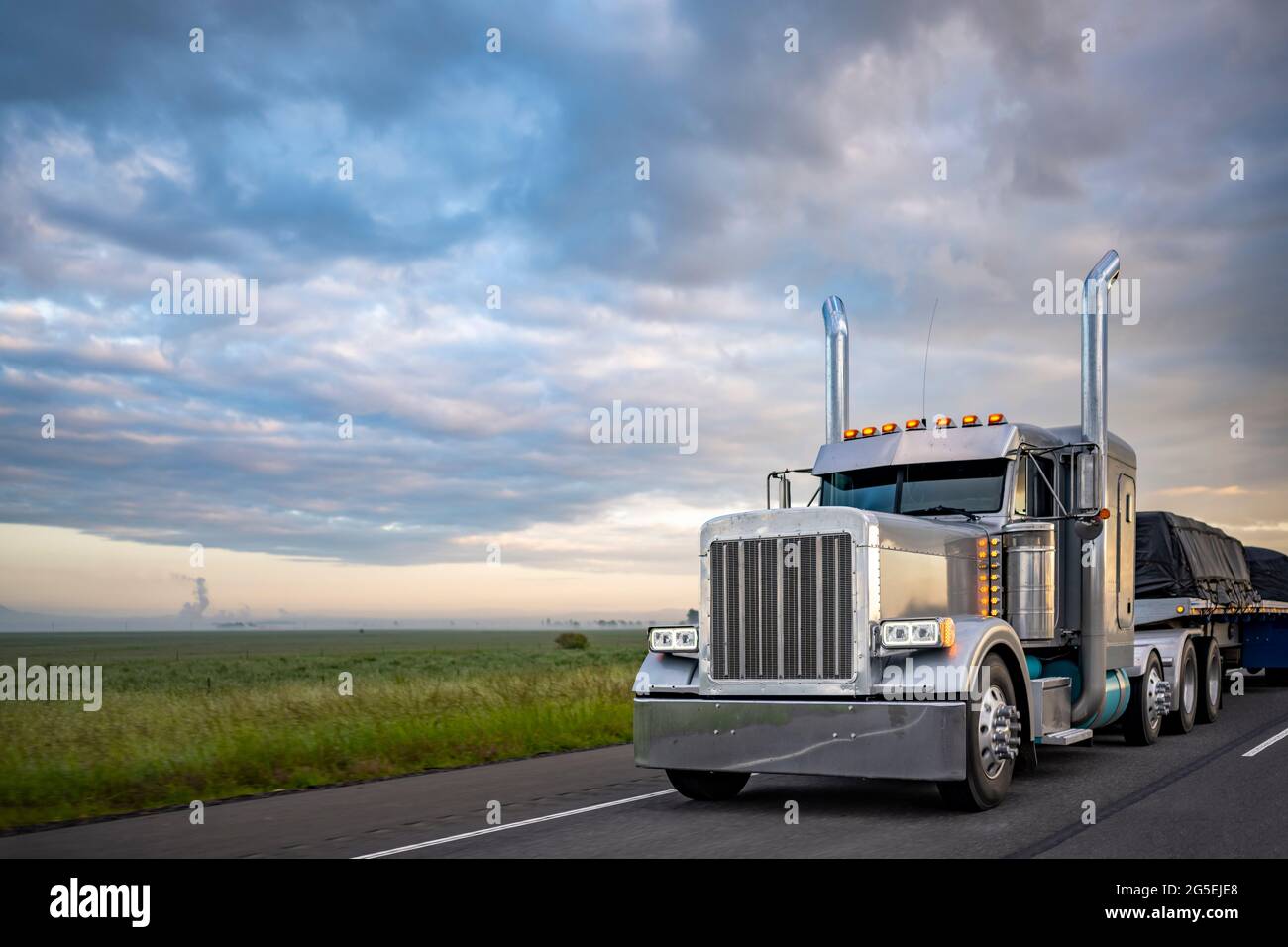 Gray classic big rig American semi truck with turned on lights and ...