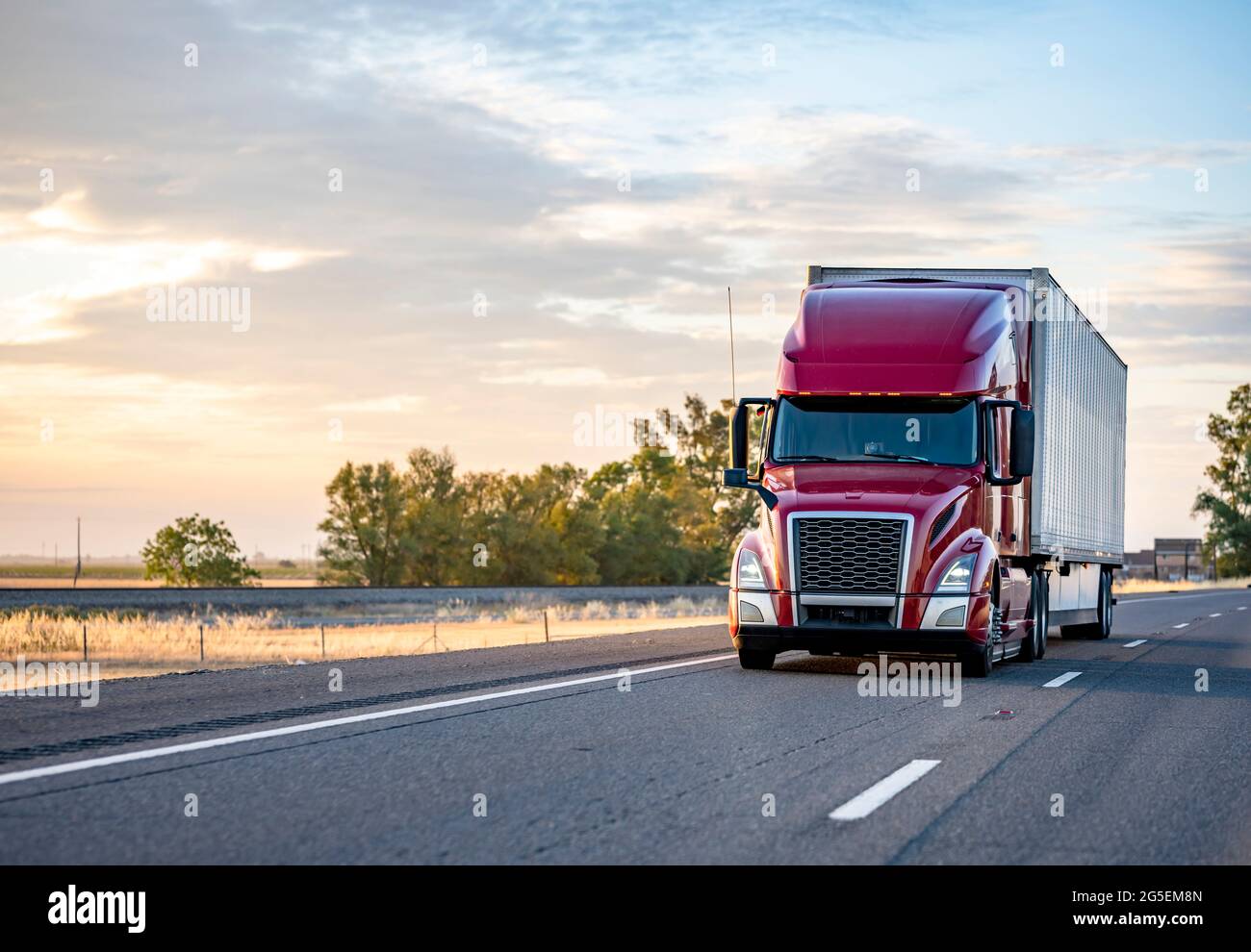 Red big rig long haul industrial semi truck with turned on headlight ...