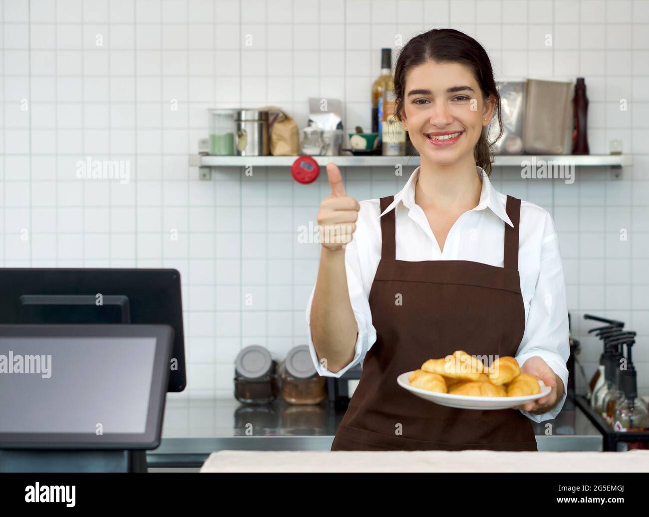 Young caucasian shopkeeper smile and raise thumbs up while holds ...