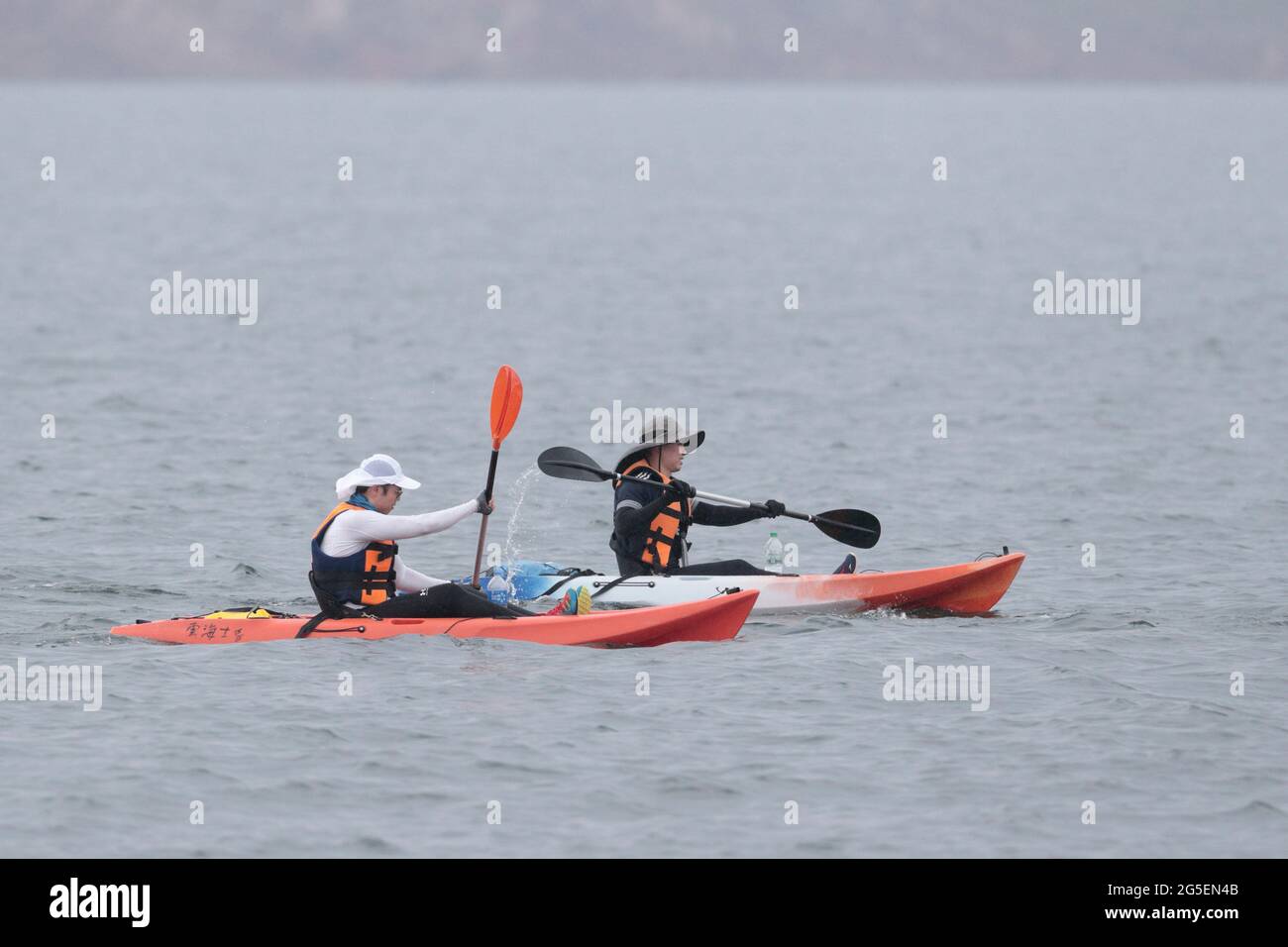 Two people paddling sea kayaks, Tolo Harbour, northeast Hong Kong ...