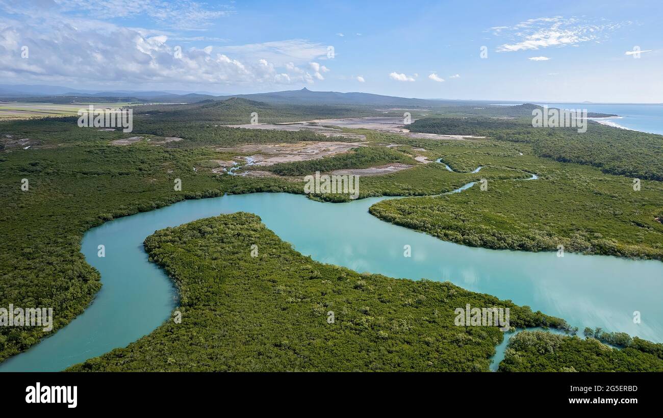 Aerial over a blue water creek flowing from the ocean and winding ...