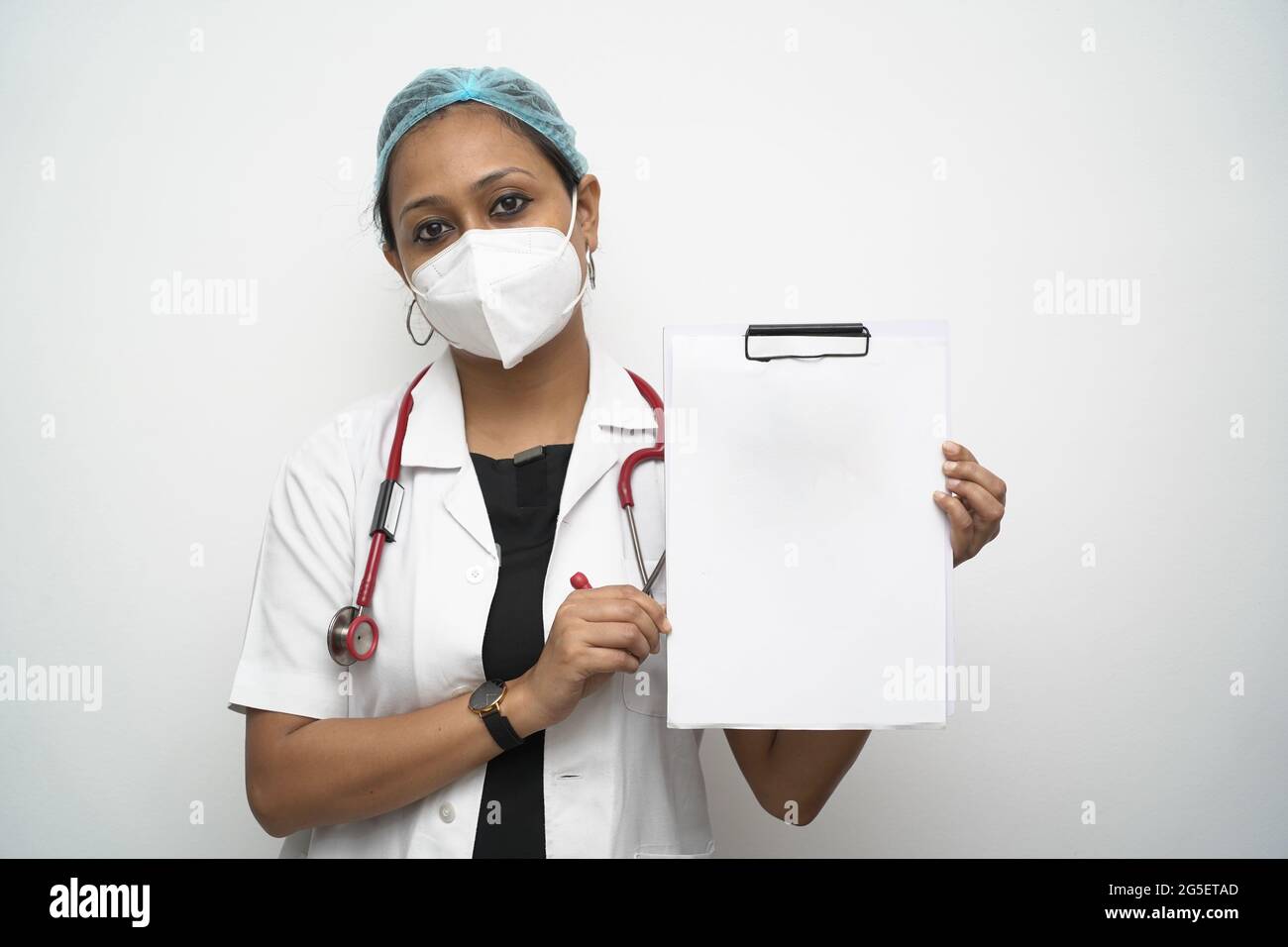 A south Indian female doctor in 30s with cap and mask showing a blank ...