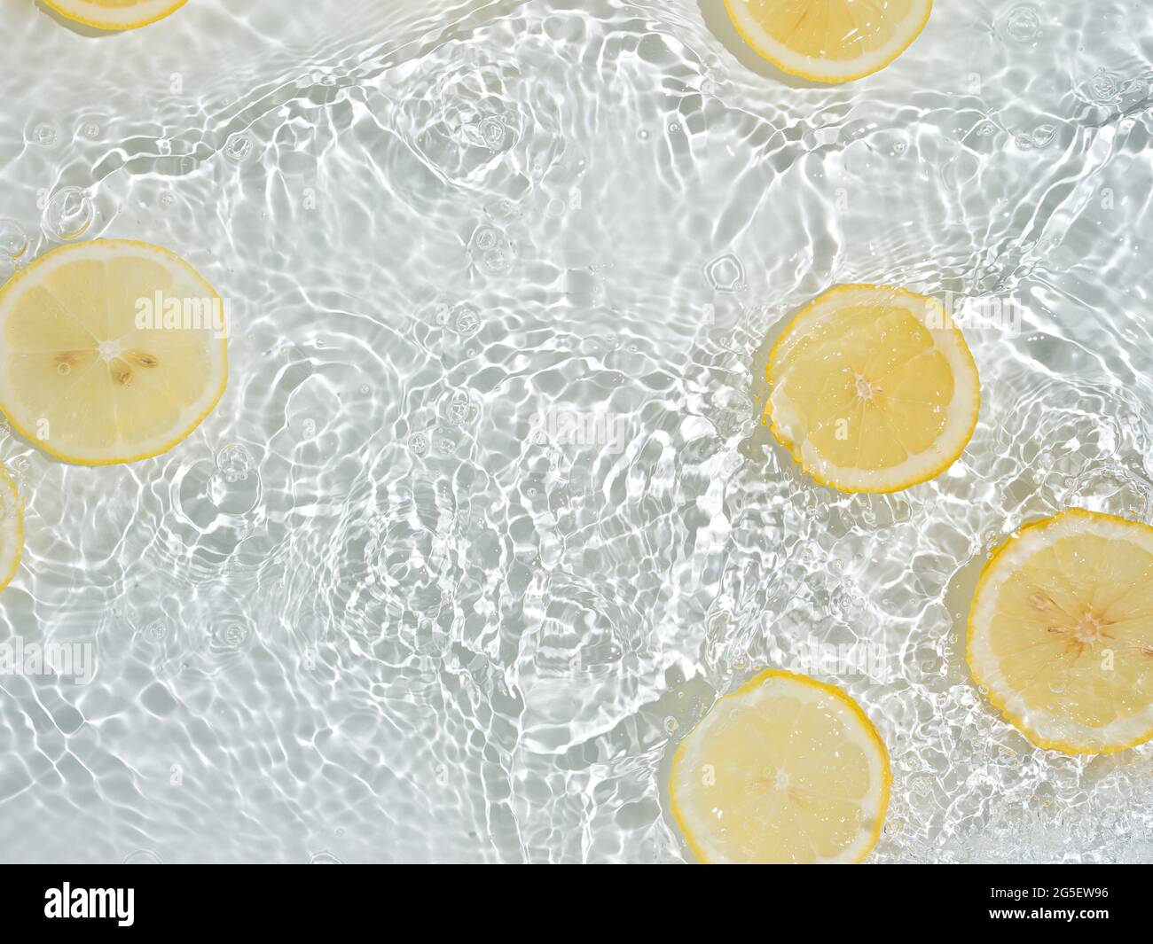 Lemon slices in clean transparent water over white background with copy ...