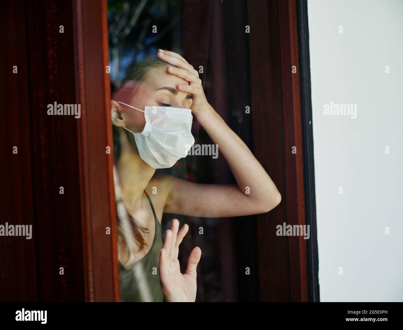 woman with closed eyes in medical mask holds hand on forehead near ...