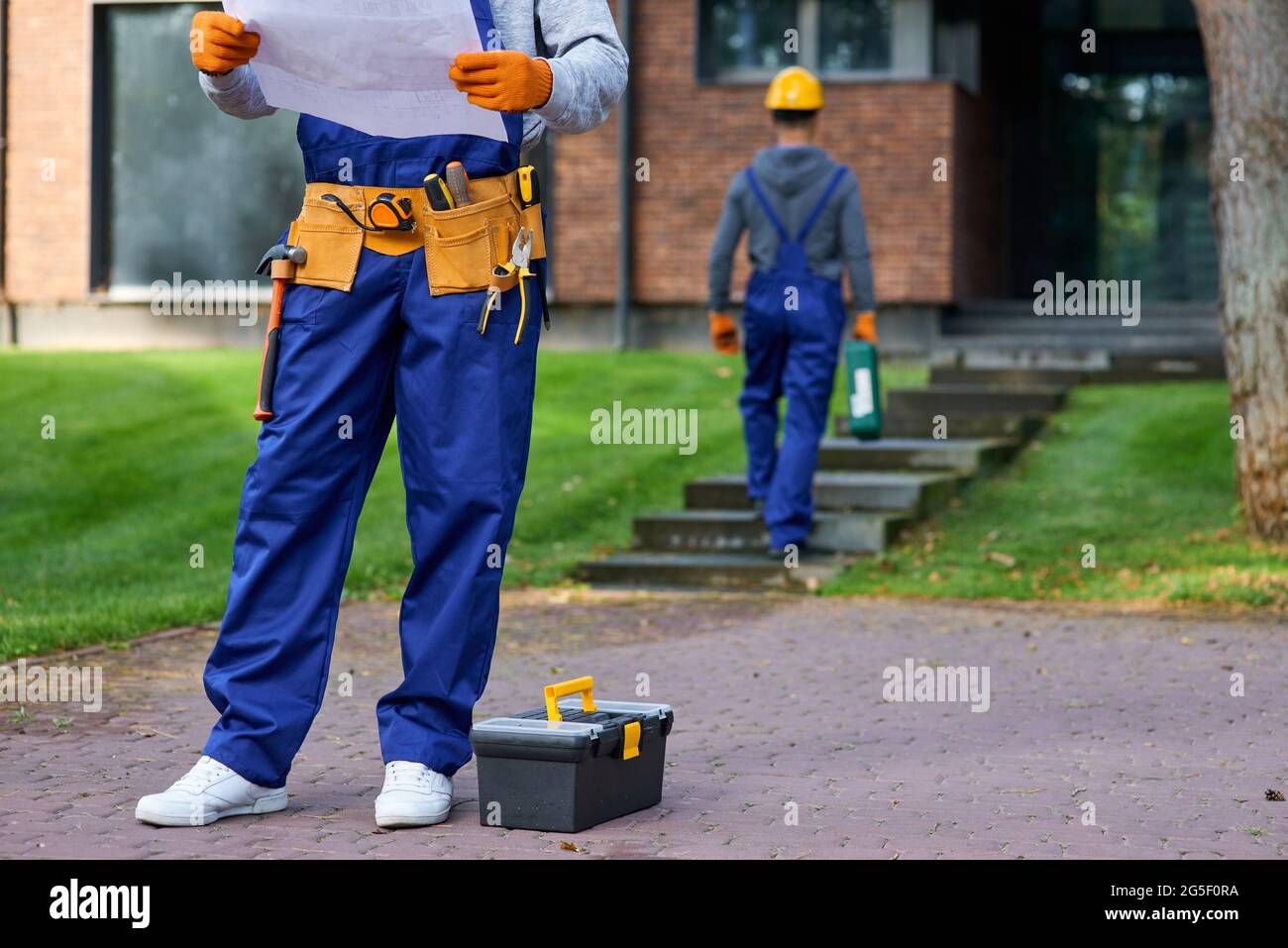 Cropped shot of male builder in blue overalls standing outdoors with ...