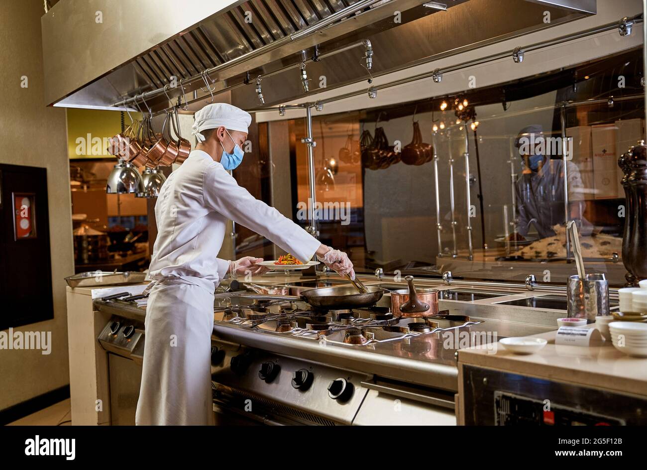 Male restaurant cook taking the rest of vegetables from pan Stock Photo ...
