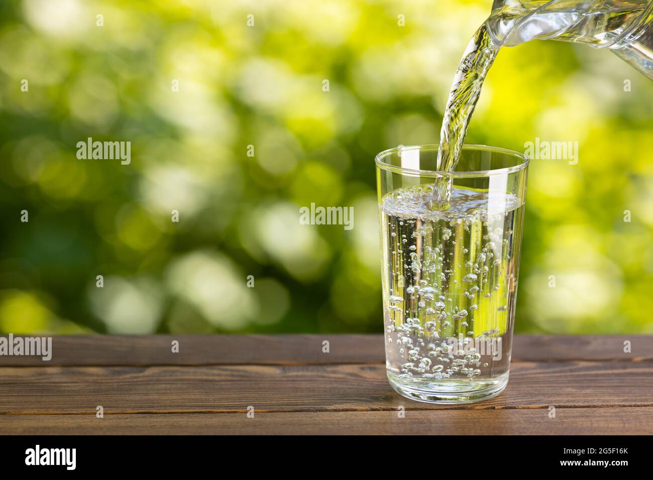 water from jug pouring into glass on table outdoors Stock Photo - Alamy