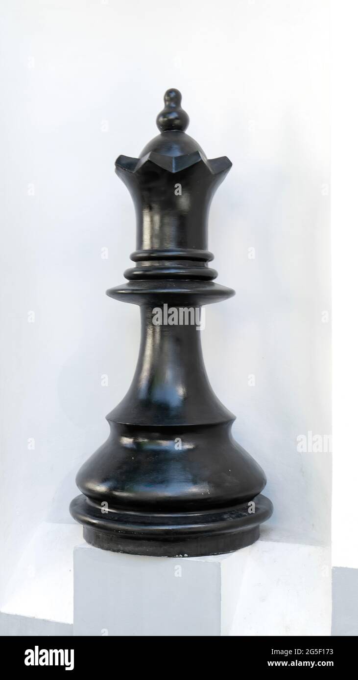 A huge chess piece of the black queen on a pedestal in the park. Black ...
