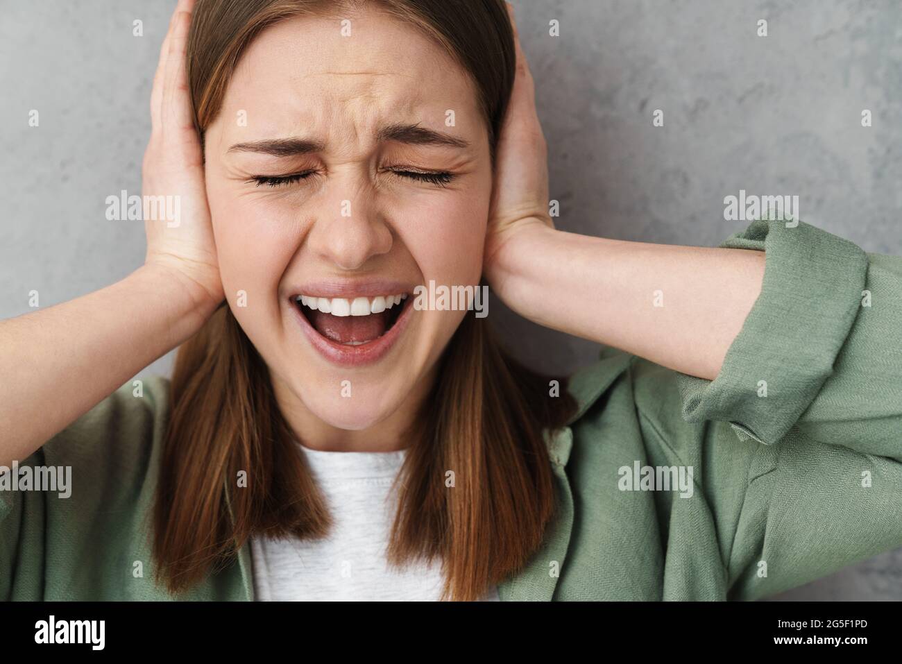 Irritated beautiful nice girl screaming and covering her ears isolated ...