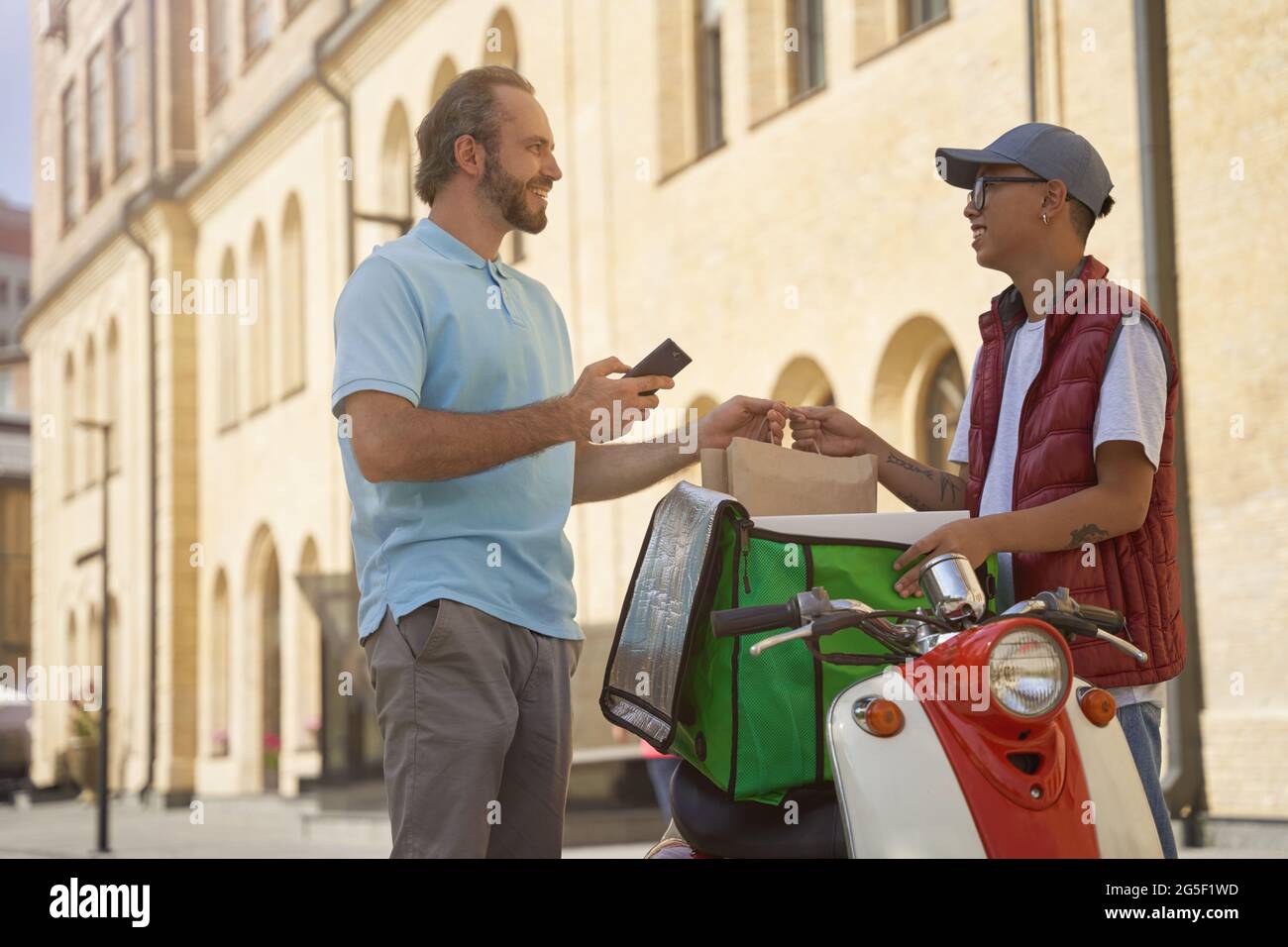 Contactless payment. Young cheerful man receiving paper bag with Stock ...
