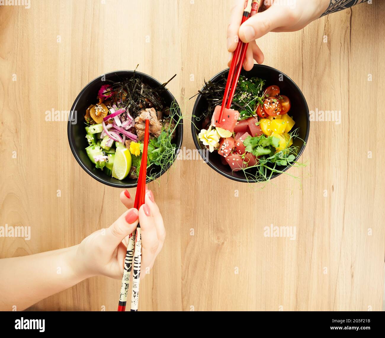 Man and woman eating poke salad with chopsticks. Dab tuna salad in a ...