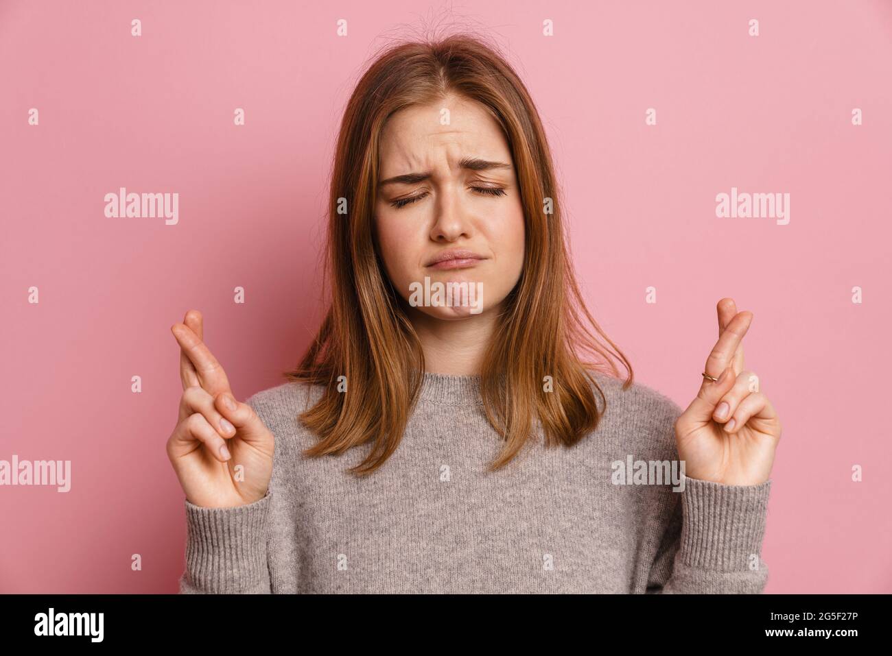 Ginger upset woman posing with fingers crossed for good luck isolated ...