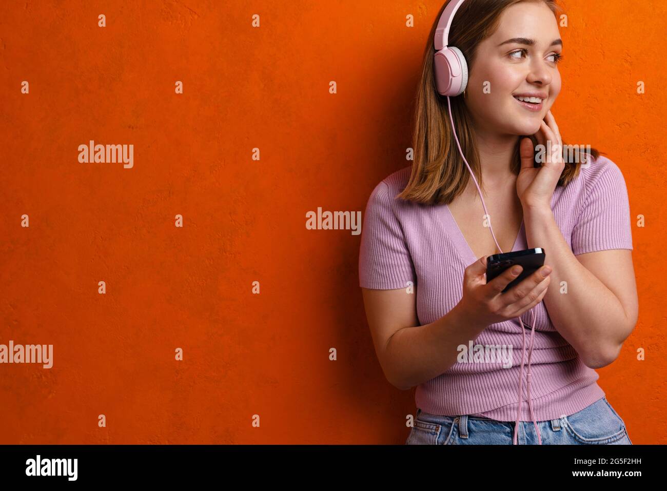 Young ginger happy woman listening music with headphones and cellphone ...