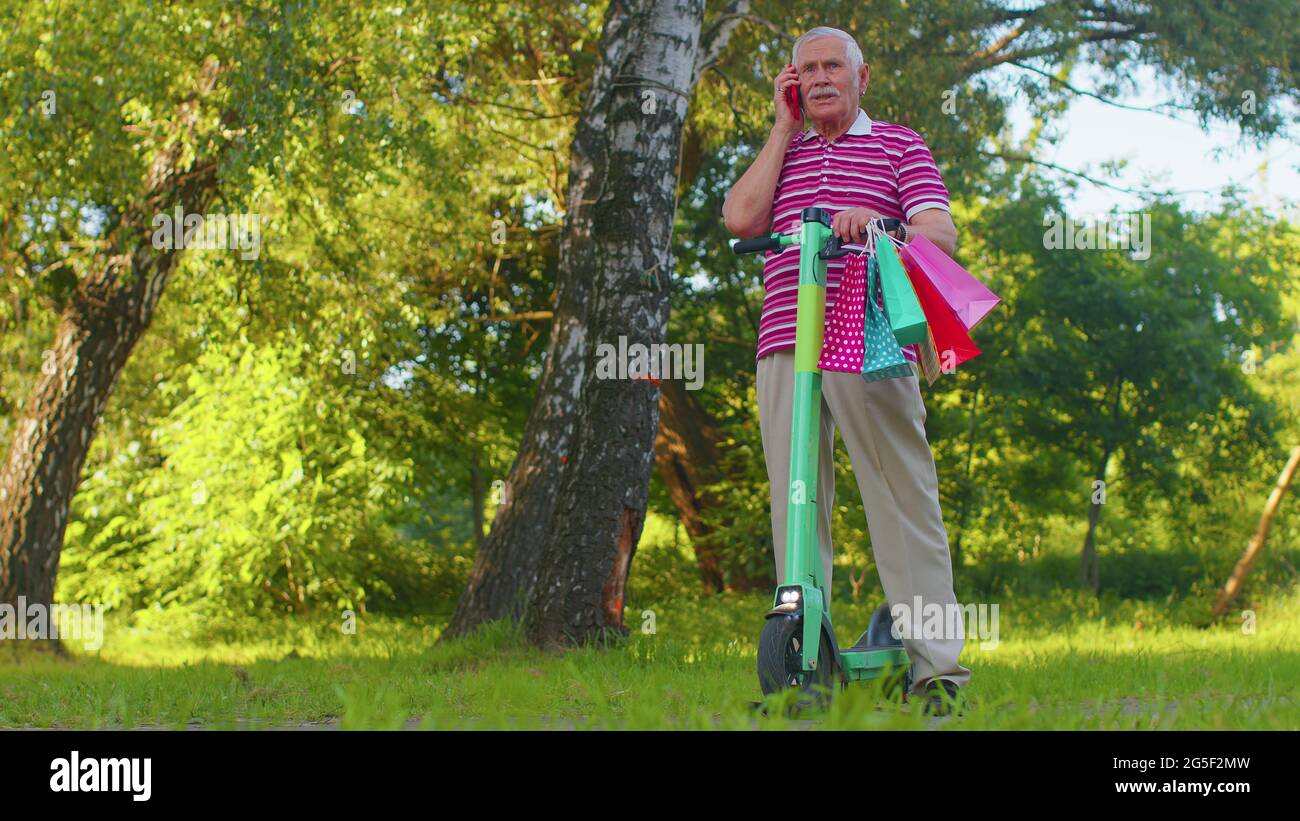 Senior old grandfather man on electric scooter with colorful shopping ...