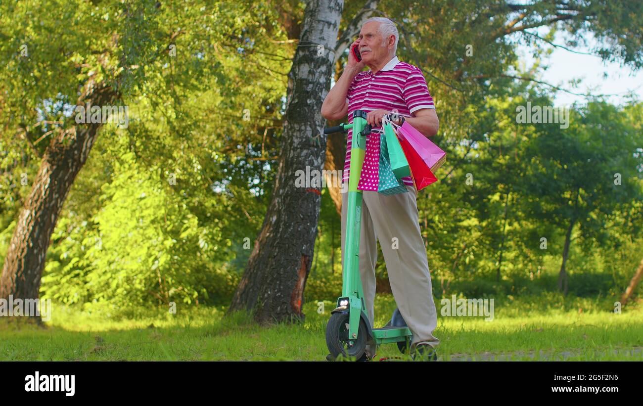 Senior old grandfather man on electric scooter with colorful shopping ...