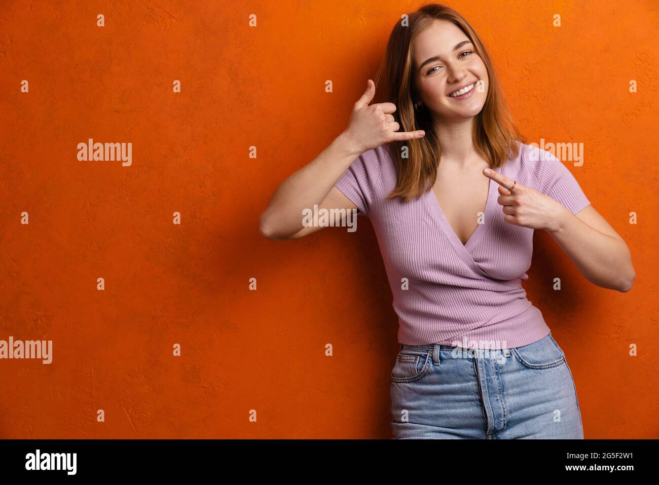 Smiling lovely young girl showing phone call gesture isolated over ...