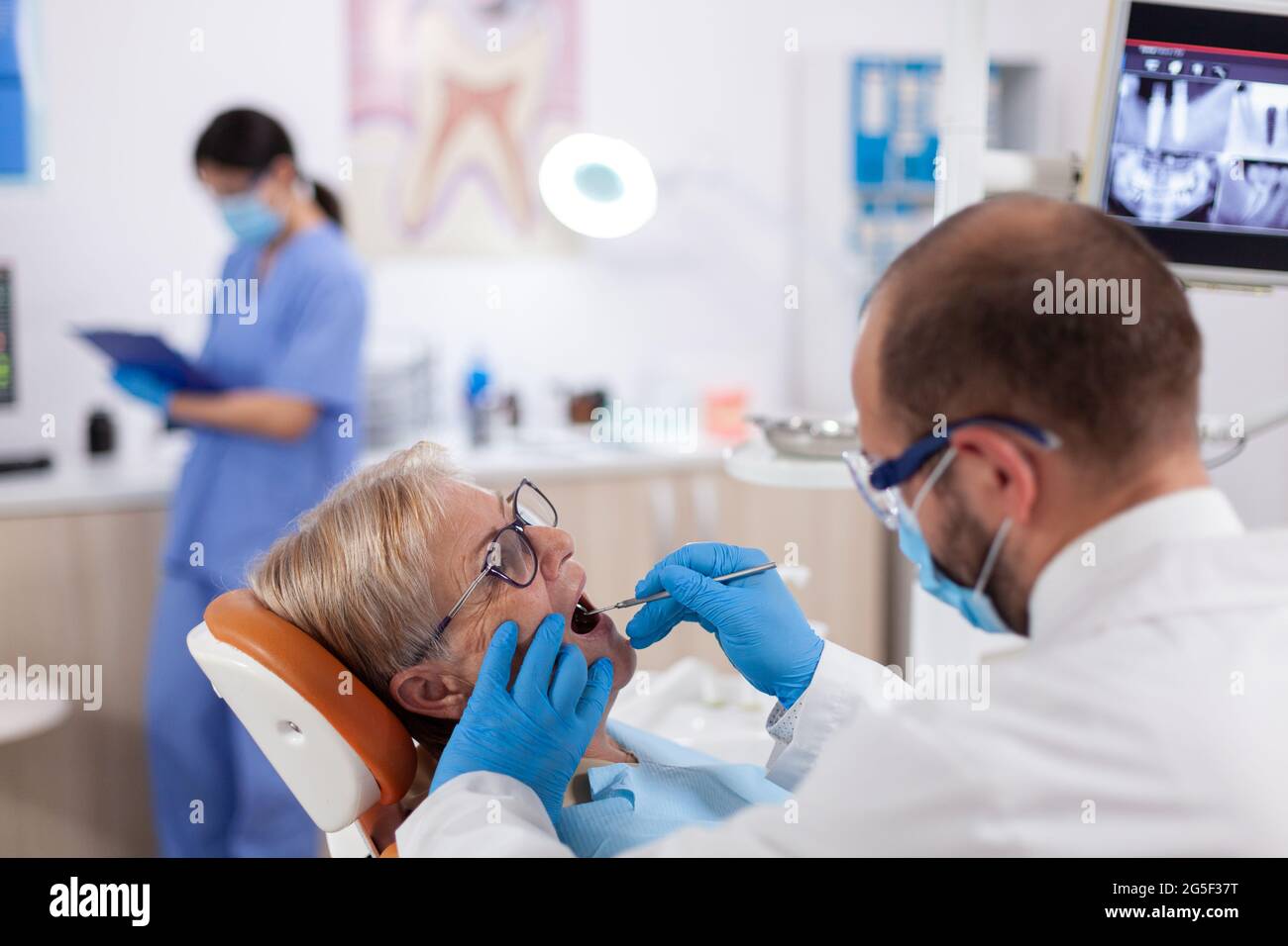 Stomatolog wearing face mask during consultation of senior woman using ...