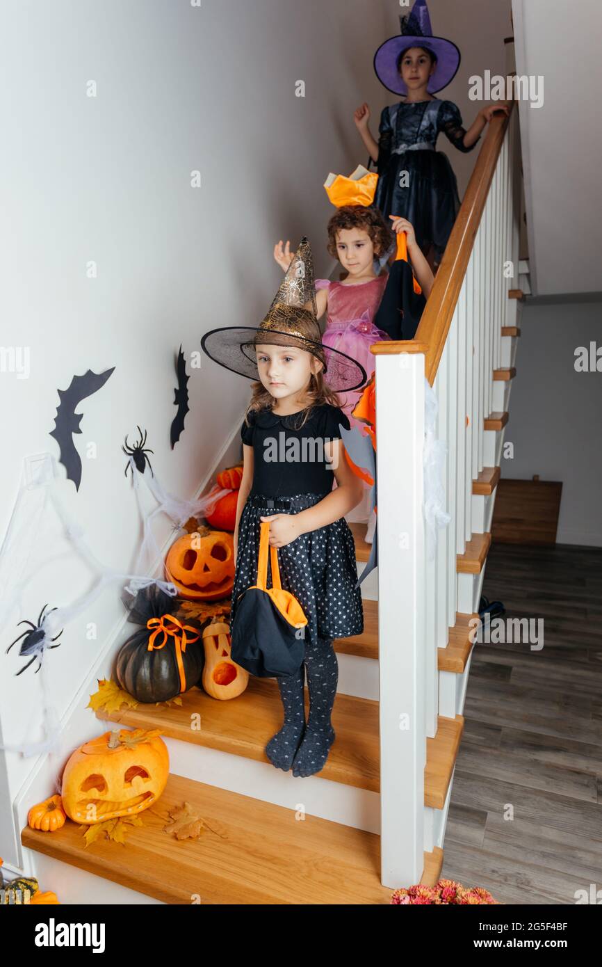 Cheerful girls wearing halloween witch costumes posing on staircase ...