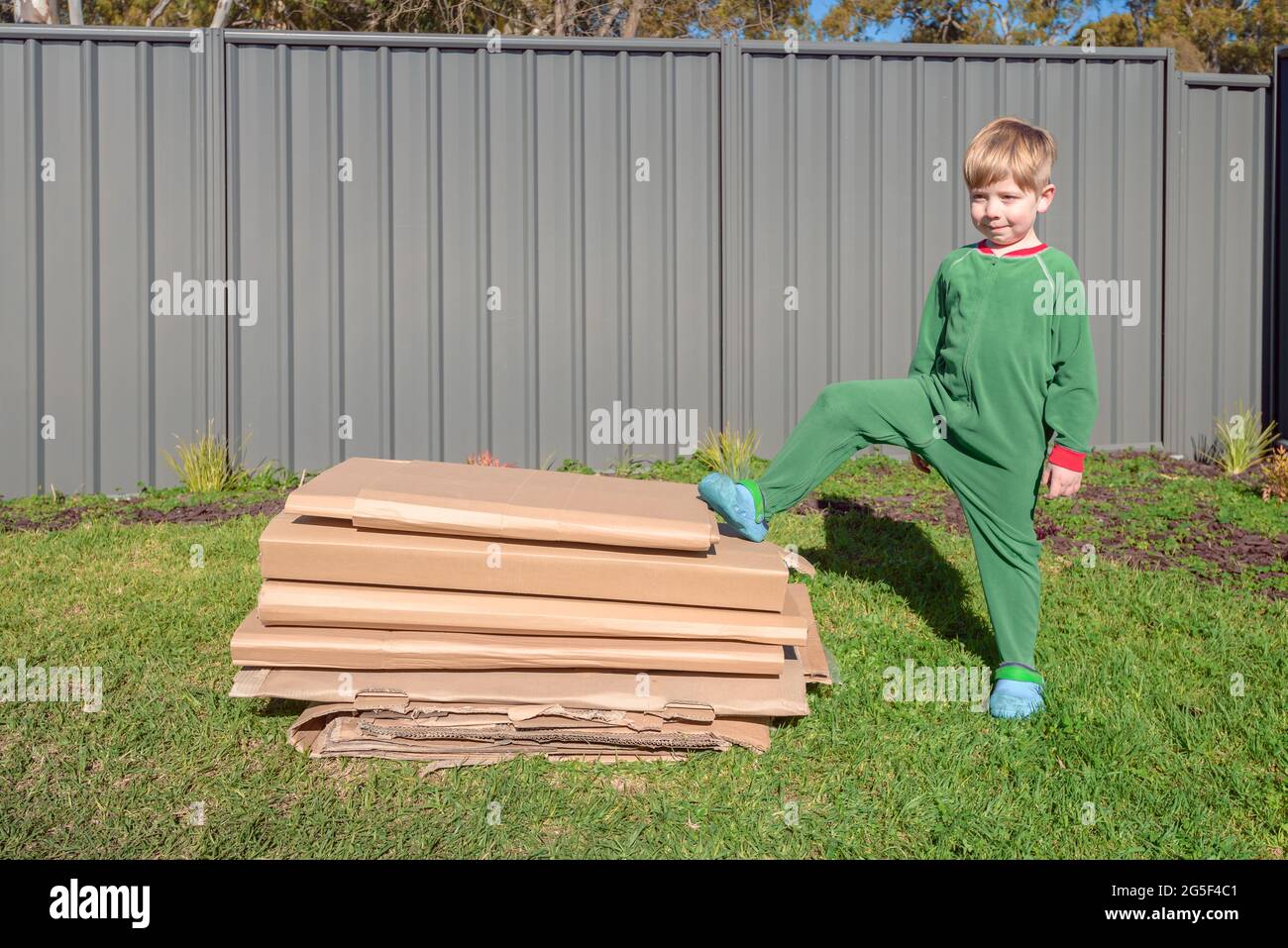Little boy standing next to a pile of crushed cartons ready for ...