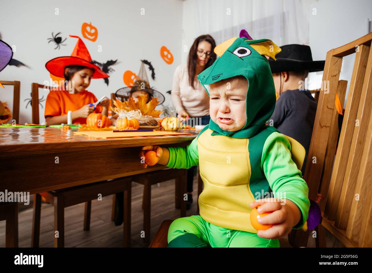 Little baby boy in green fancy costume sitting and crying Stock Photo ...