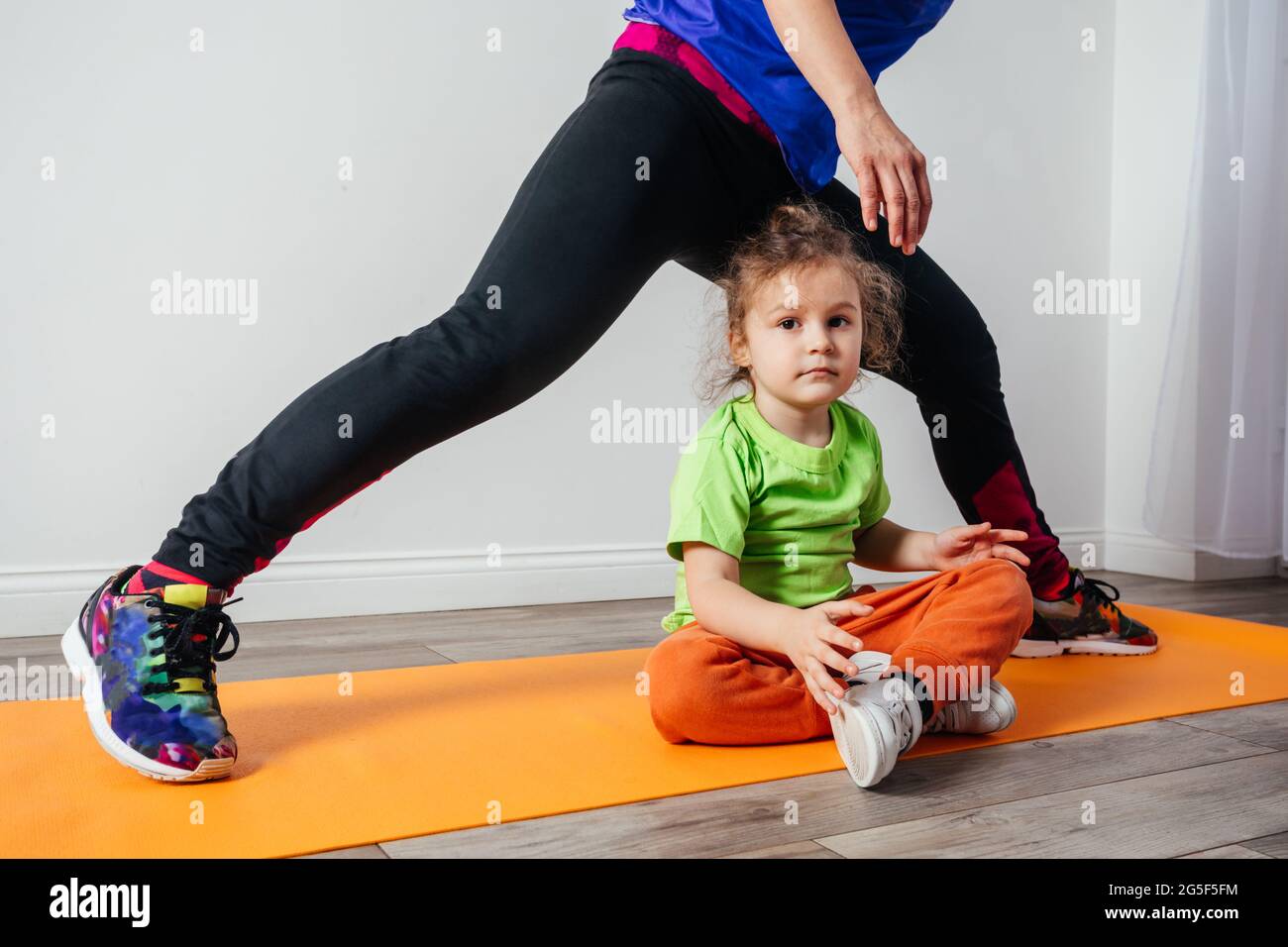 Cute little boy is bored while mother doing morning yoga Stock Photo ...
