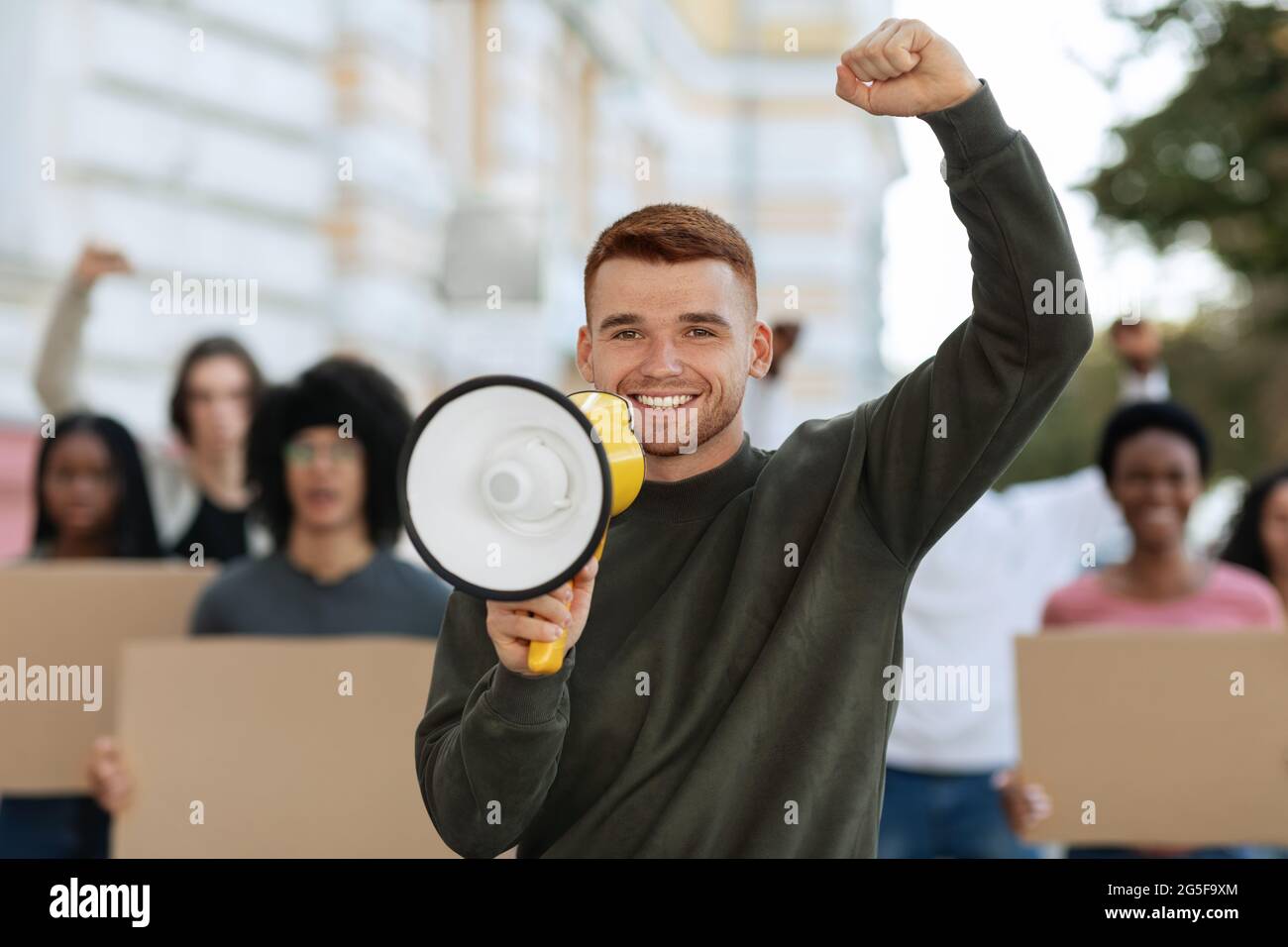 Emotional guy activist with megaphone on the street, chanting slogans ...