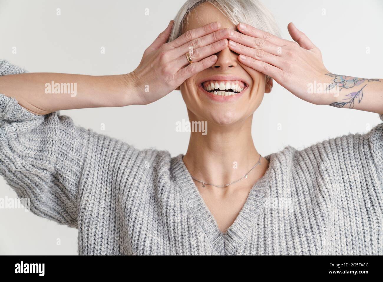 Happy silver girl covering her eyes while laughing at camera isolated ...