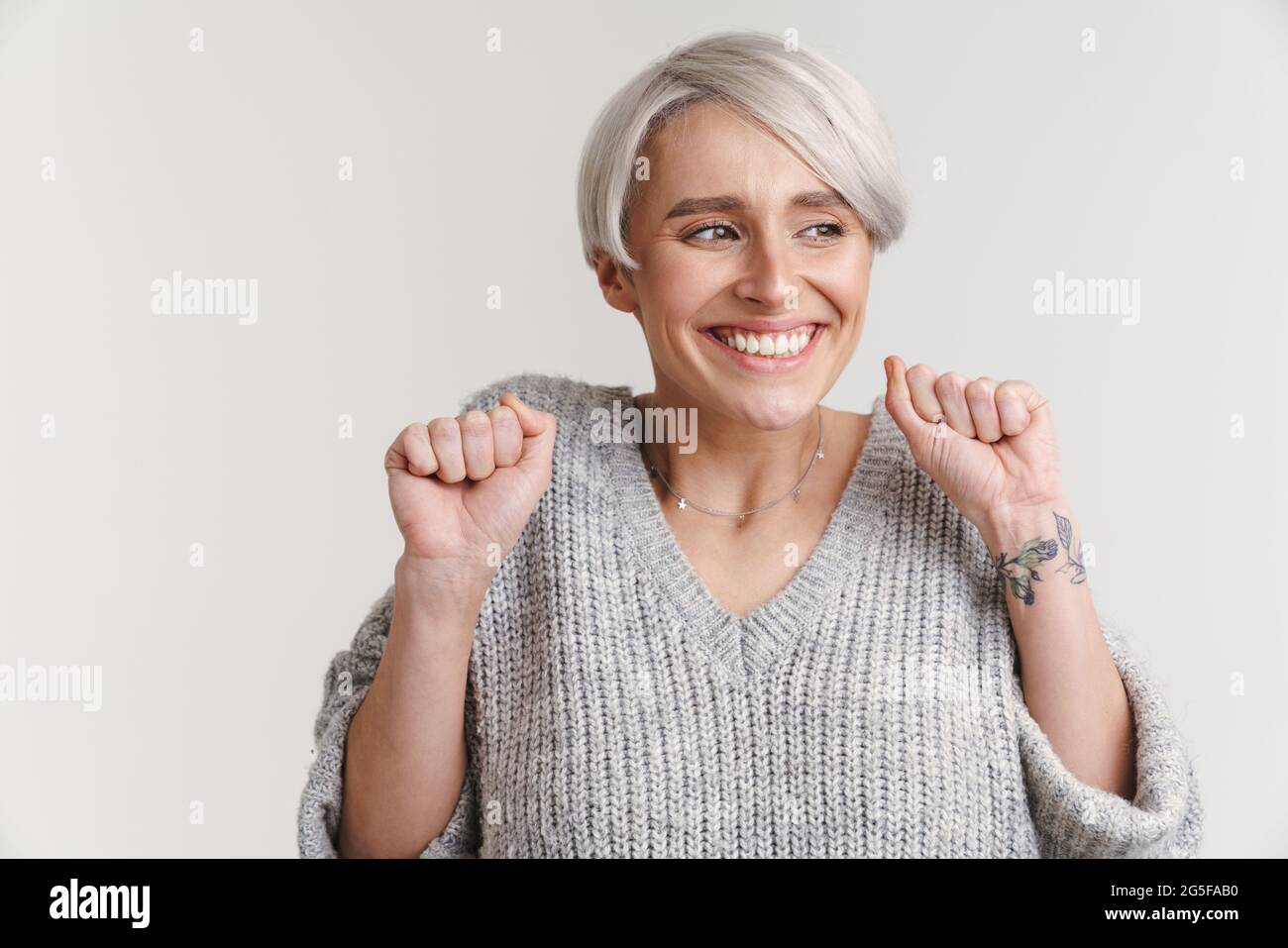 Young grey-haired woman smiling with clinched fists isolated over white ...