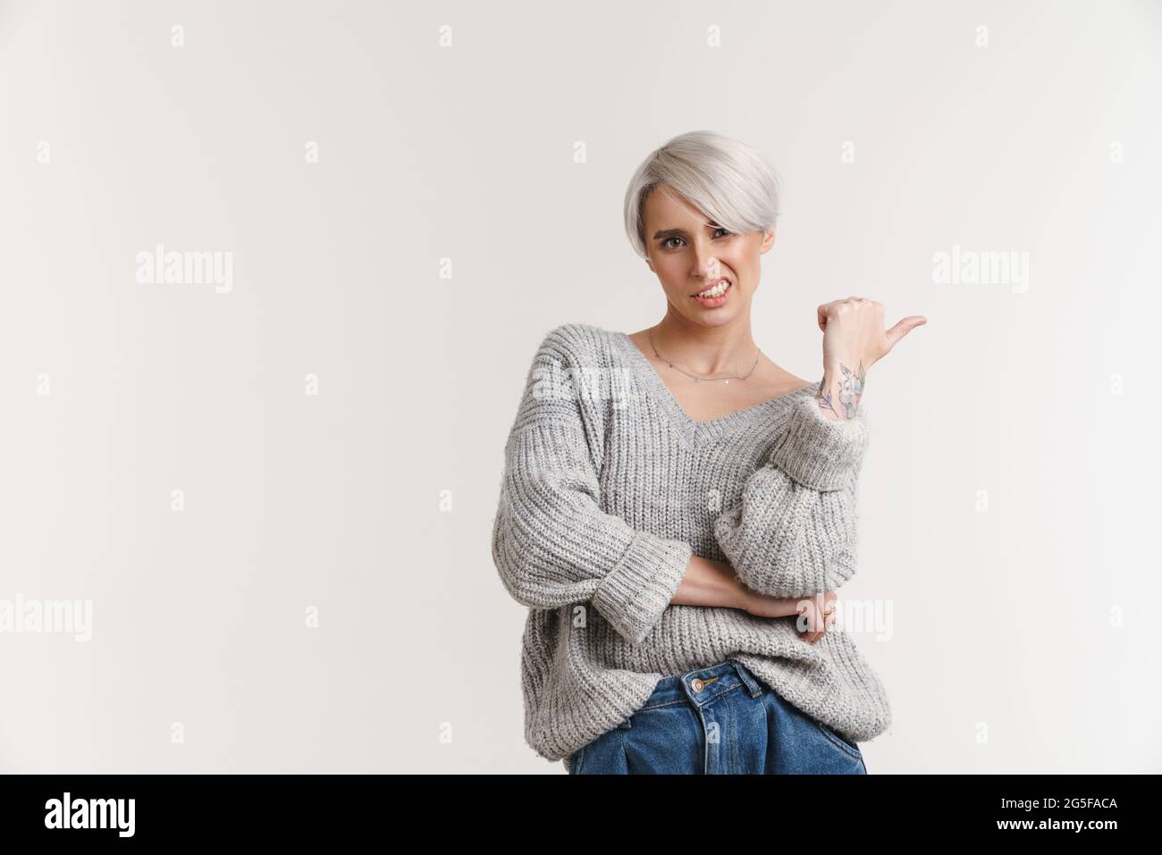 Confused beautiful silver girl grimacing and pointing finger aside ...