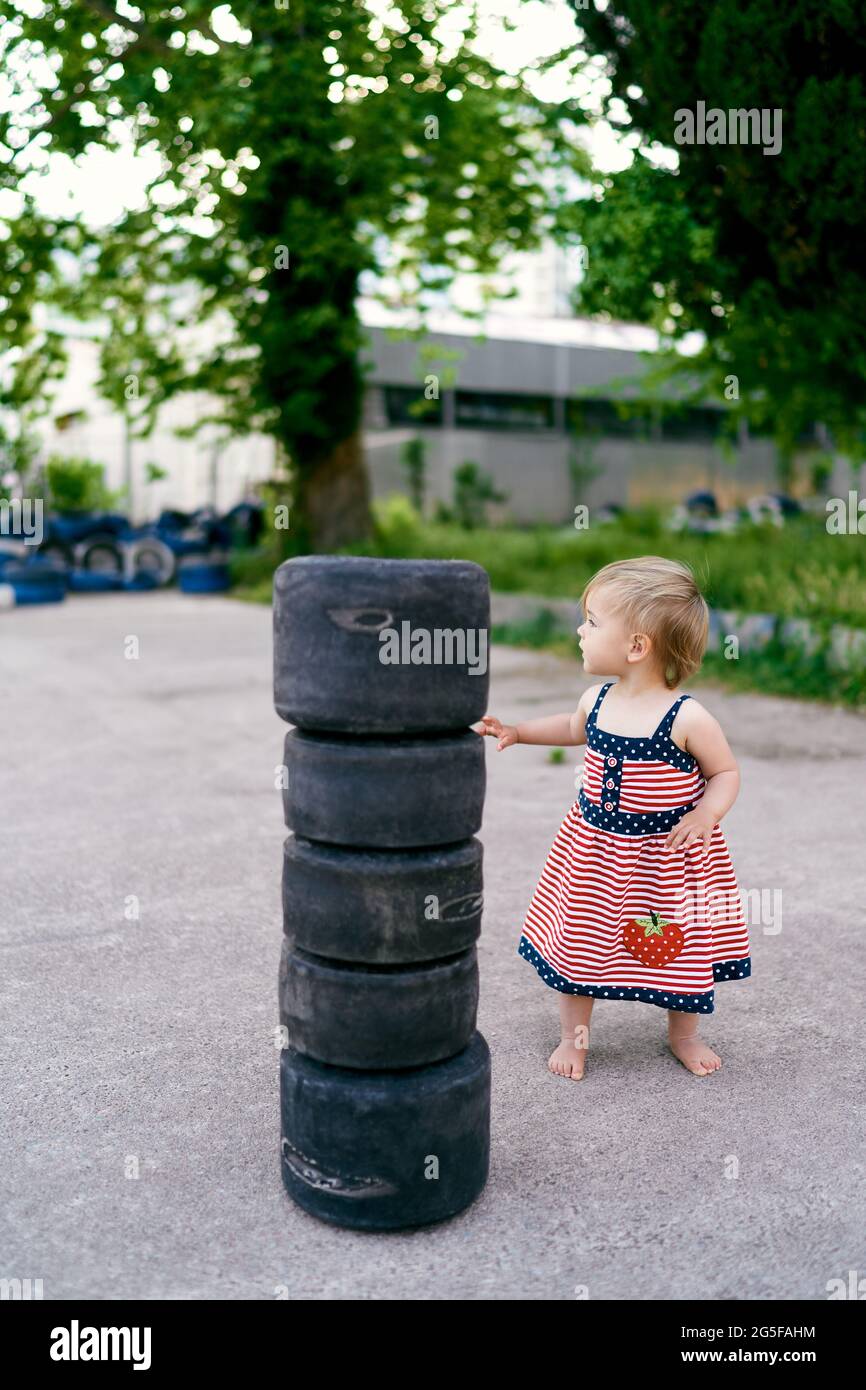 Little girl stands near a pile of small tires Stock Photo - Alamy
