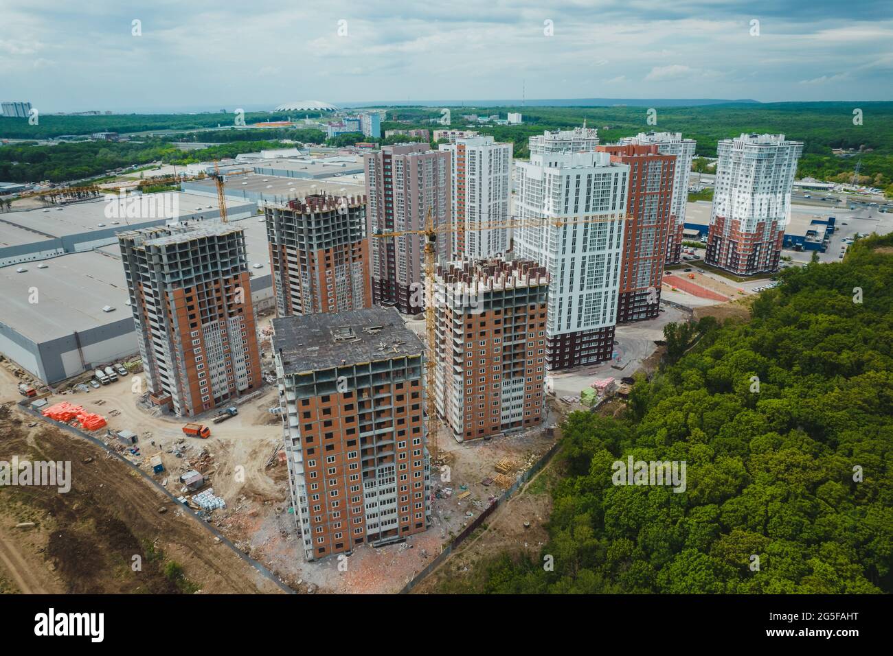 Construction yard of multistory living building with hoisting cranes ...