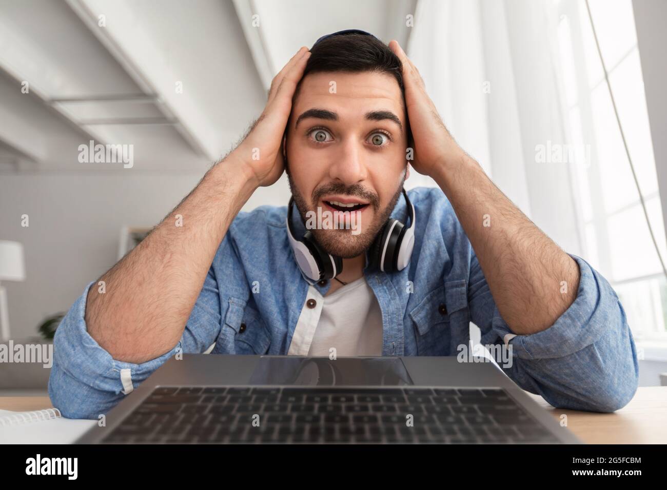 Wow. Portrait of young surprised jewish man in kippah looking at screen ...