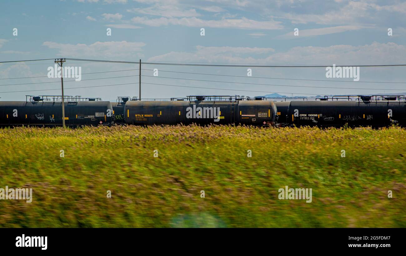 An oil freight train with oil cars passing through the prairie on the ...