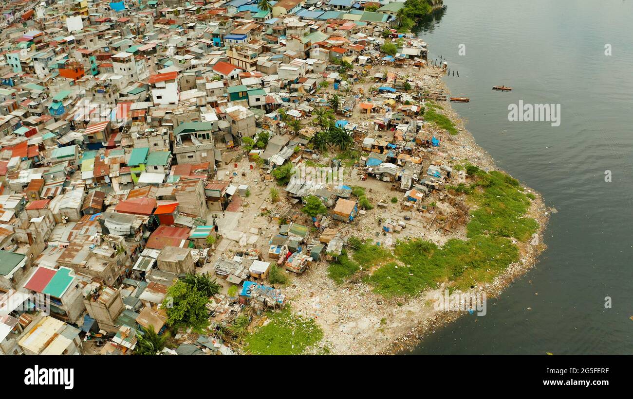 Slums in Manila on the bank of a river polluted with garbage, aerial ...