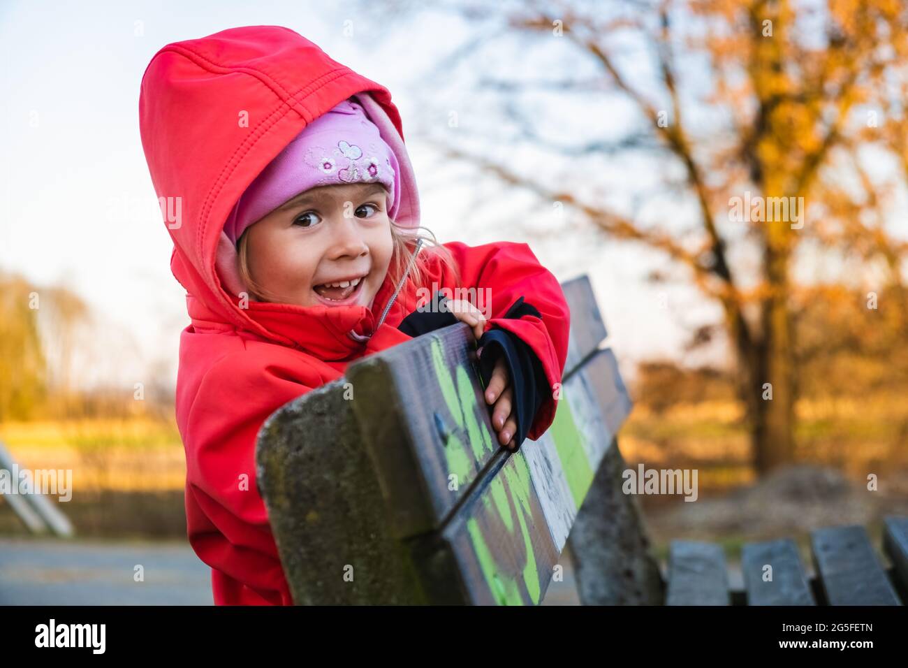 Child in early spring outdoors hanging on bench in rural area Stock ...