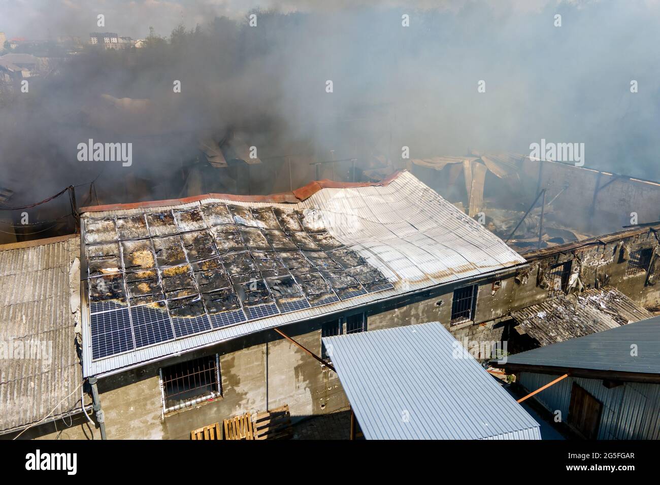 Aerial view of ruined building on fire with collapsed roof and rising ...