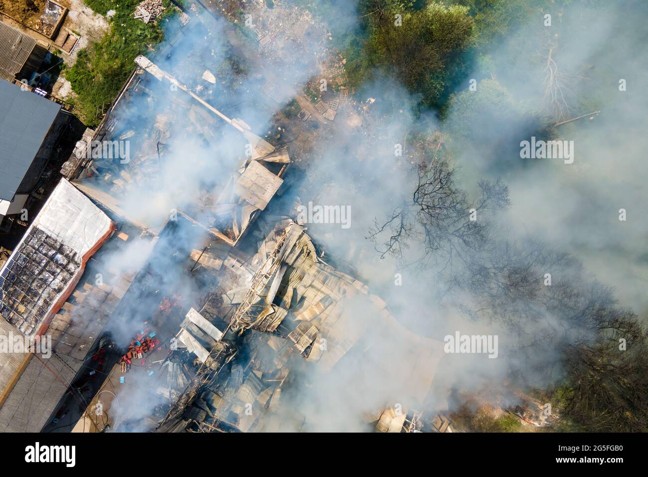 Aerial view of ruined building on fire with collapsed roof and rising ...