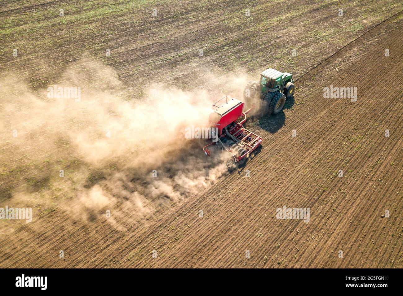 Top down aerial view of green tractor cultivating ground and seeding a ...