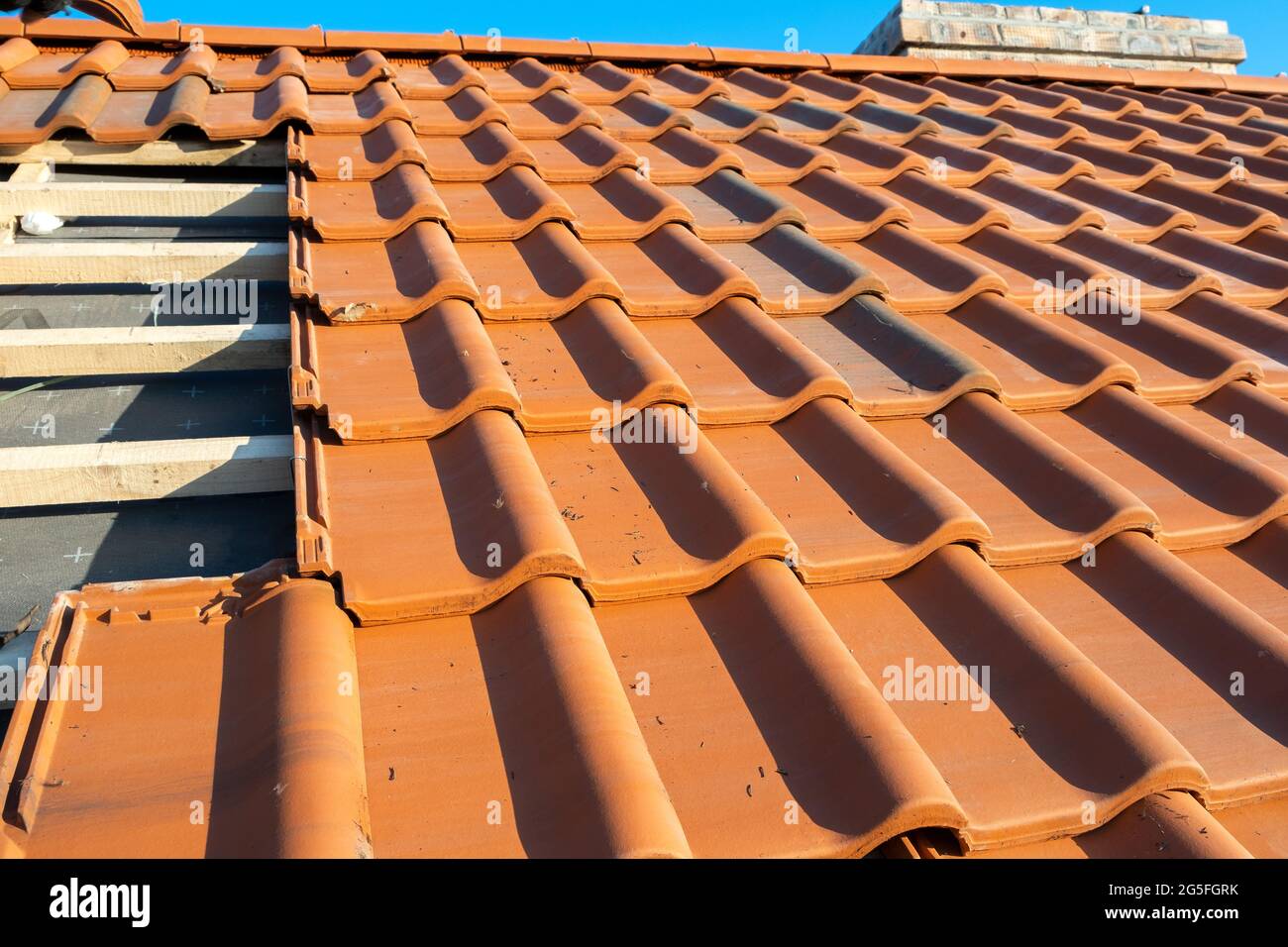 Overlapping rows of yellow ceramic roofing tiles mounted on wooden ...