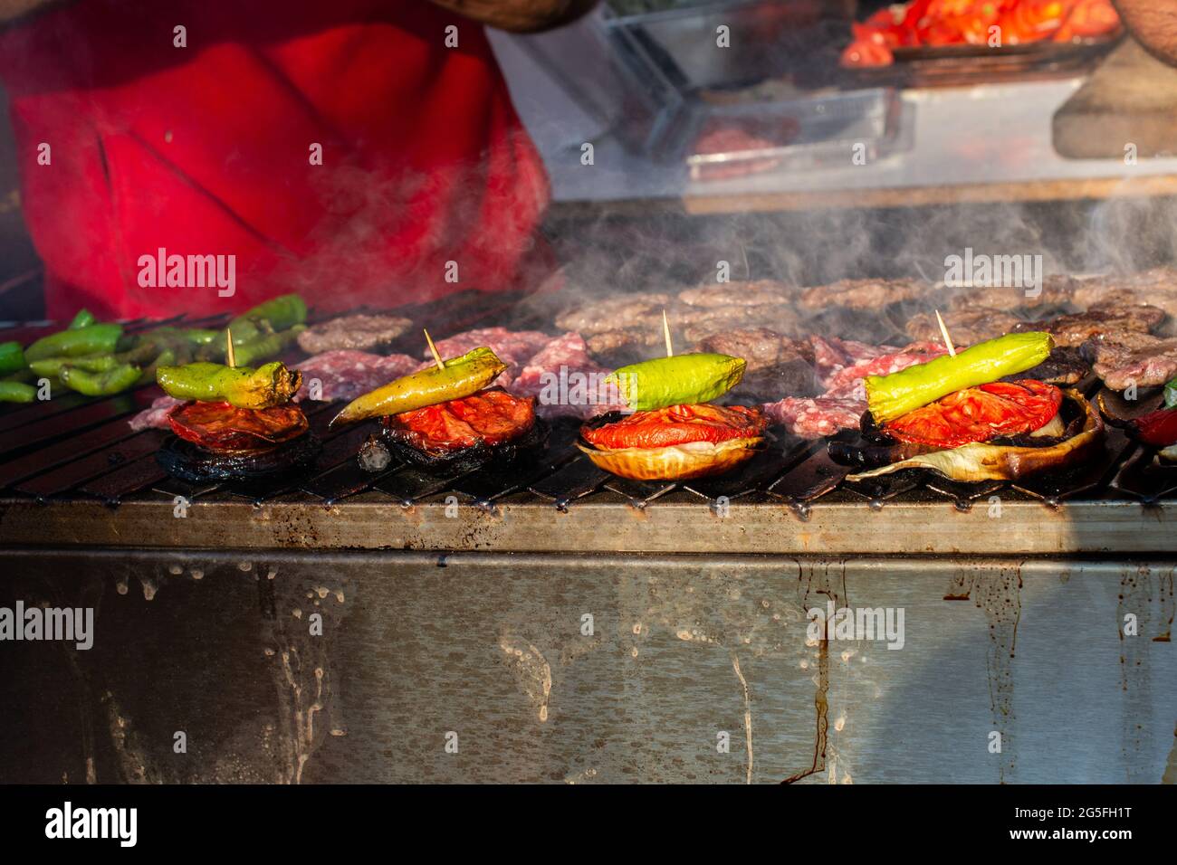 A kebab preparation process, meat and vegetables on a grill outside ...