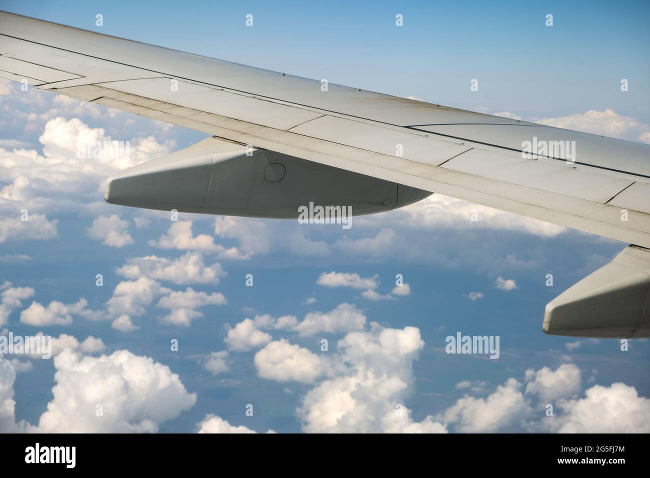 View of jet airplane wing from inside flying over white puffy clouds in ...