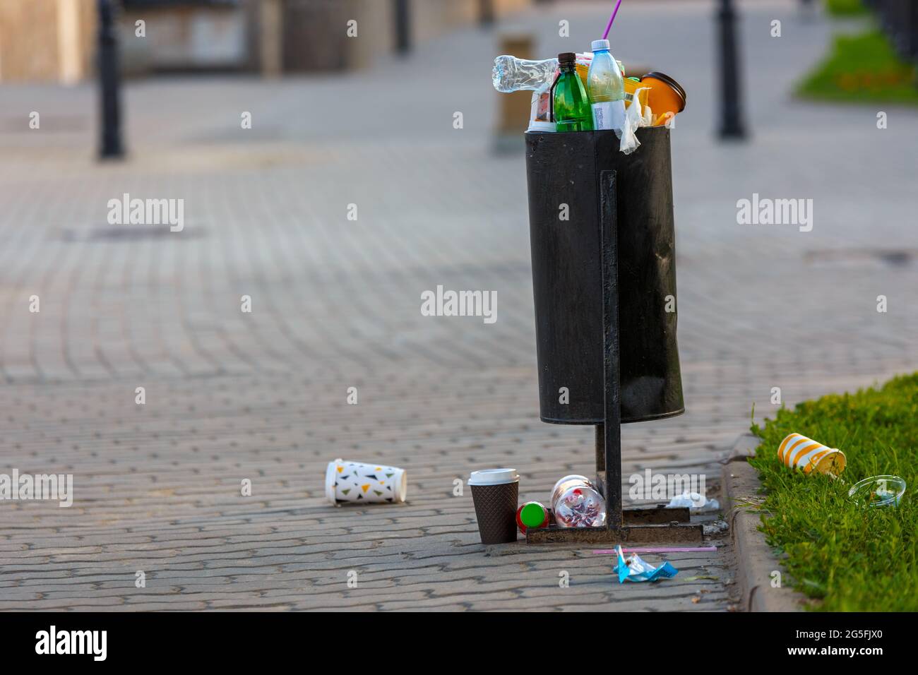 overflowing trash can on the sidewalk pavement at summer daylight Stock ...