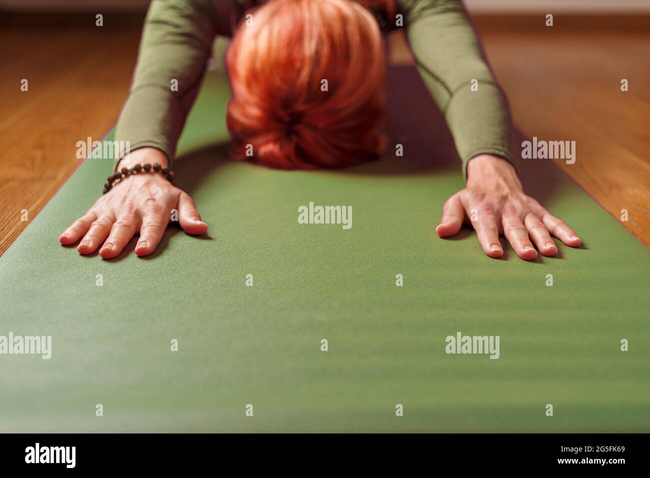 A girl does yoga in Astana on a green mat. Healthy lifestyle, asanas ...